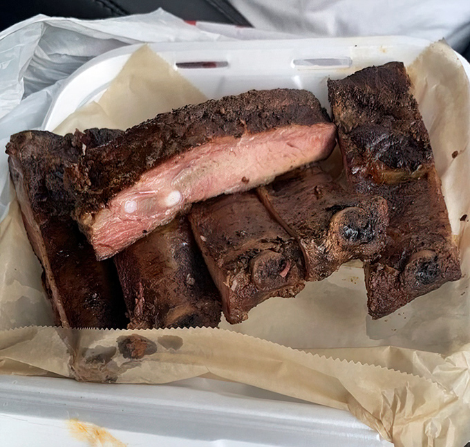 These ribs showcase that perfect moment when smoke meets meat—the pink smoke ring is like nature's way of applauding good BBQ.