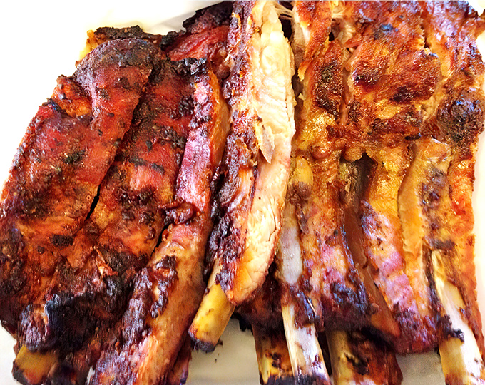 These ribs showcase that perfect pink smoke ring—the barbecue equivalent of a designer label. The bark has more character than most Hollywood scripts.