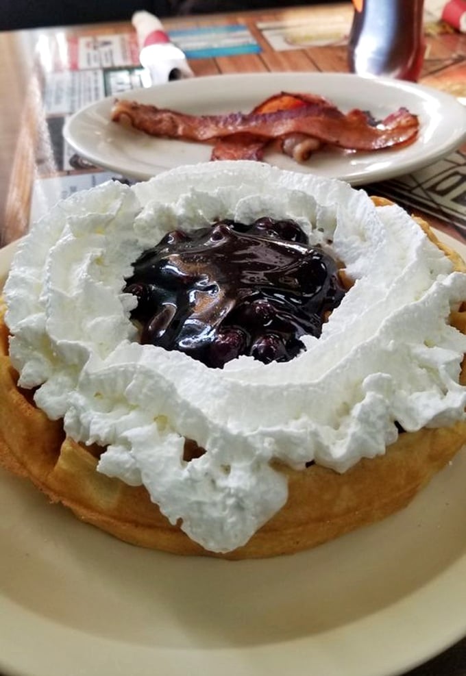 Waffle architecture at its finest—a sturdy foundation supporting whipped cream mountains and a blueberry compote lake. Breakfast or dessert? Why choose?