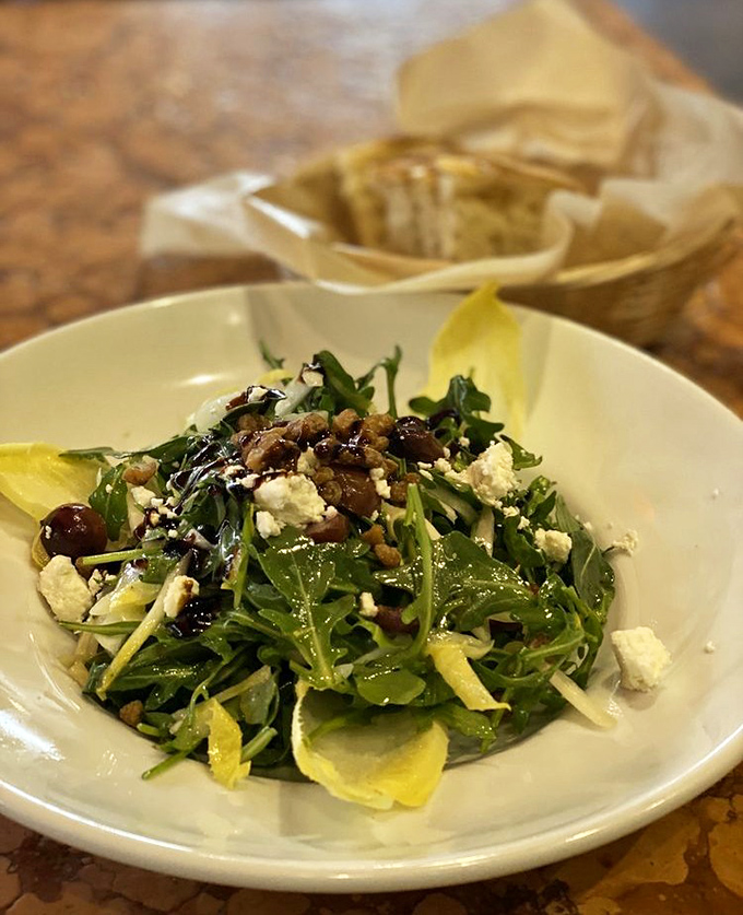 A salad that actually deserves to be ordered at a pasta restaurant—arugula, cheese, and olives playing together like old friends at a Mediterranean reunion.