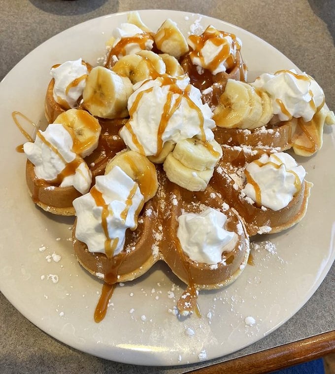 Banana-topped French toast with caramel drizzle and whipped cream—dessert masquerading as breakfast, and nobody's complaining.