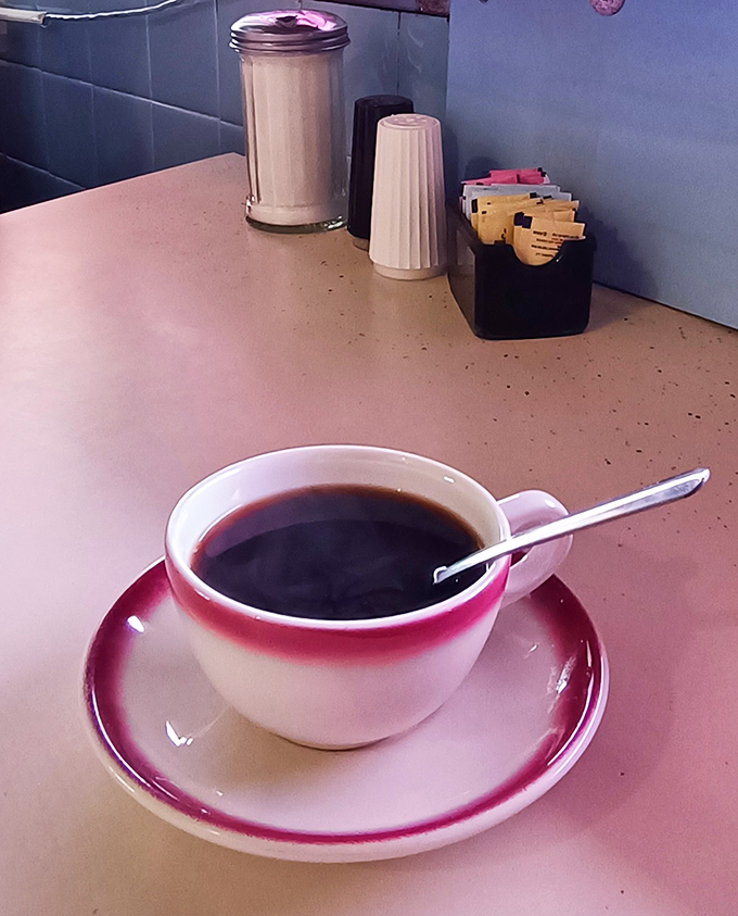 The coffee comes in that perfect pink-rimmed mug that somehow makes it taste better—diner science that no laboratory could ever replicate.