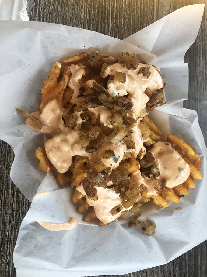 Waffle fries dressed in sauce and grilled onions—proof that even side dishes deserve their moment in the spotlight.