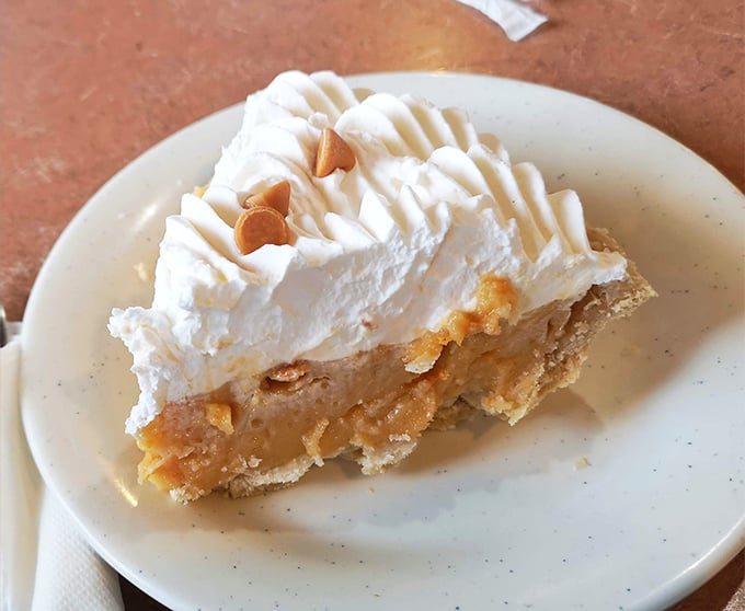 Butterscotch pie crowned with a cloud of whipped cream—the kind of dessert that makes you seriously consider ordering a second slice before finishing the first.