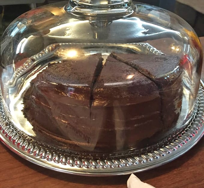 Beneath that glass dome lies chocolate cake so rich it should have its own tax bracket. Save room or live with regret—your choice.