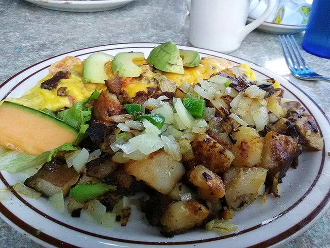 Breakfast alchemy at its finest—potatoes crisped to golden perfection alongside an omelet that's practically bursting with California sunshine.