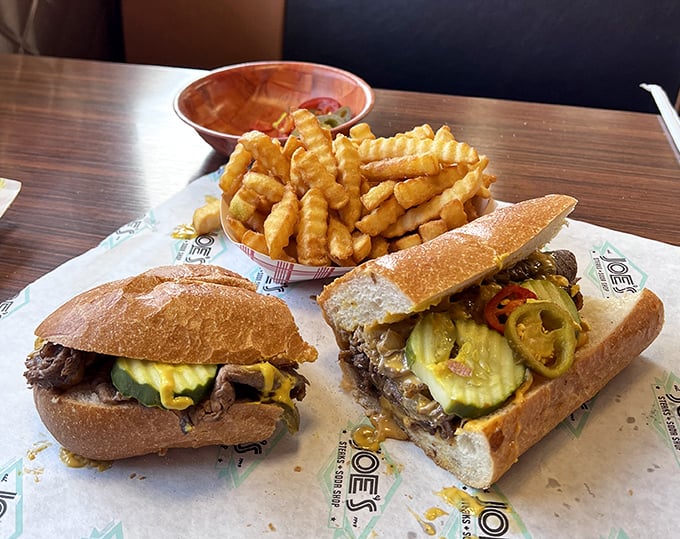 Two cheesesteaks having a serious conversation with a basket of fries—the kind of meeting you definitely want to crash.