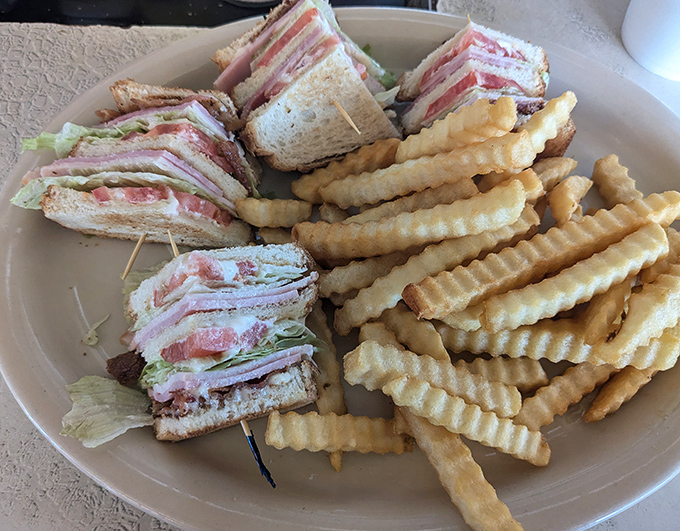 The club sandwich—architecture you can eat, with layers so precisely stacked they'd make Frank Lloyd Wright put down his blueprints and pick up a fork.
