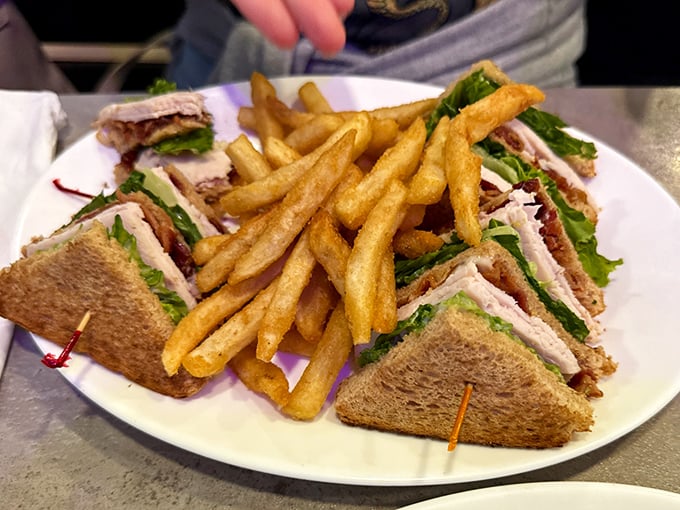 The club sandwich—that triple-decker marvel where geometry and gastronomy meet, with golden fries standing guard like delicious sentinels.