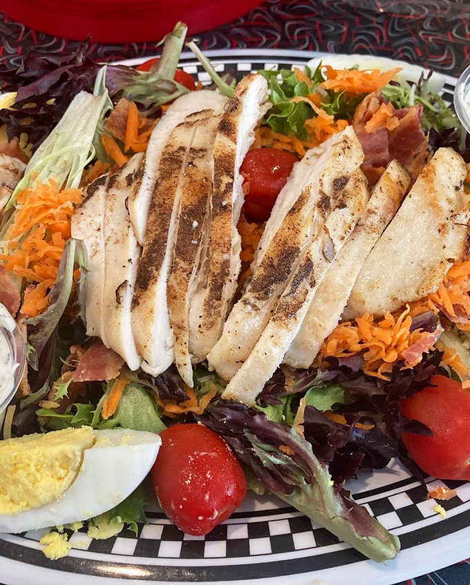 This isn't just a cobb salad—it's a colorful landscape of grilled chicken, fresh vegetables, and possibility, all on a checkered-rim plate.