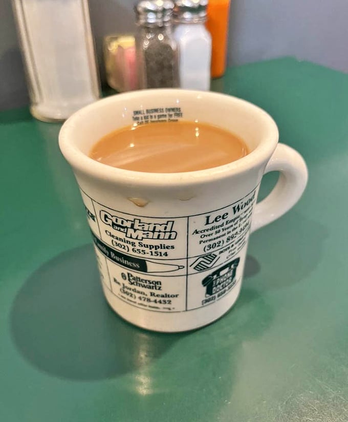 The coffee mug—advertising local businesses and filled with that honest diner brew that doesn't need a fancy origin story to wake you up right.