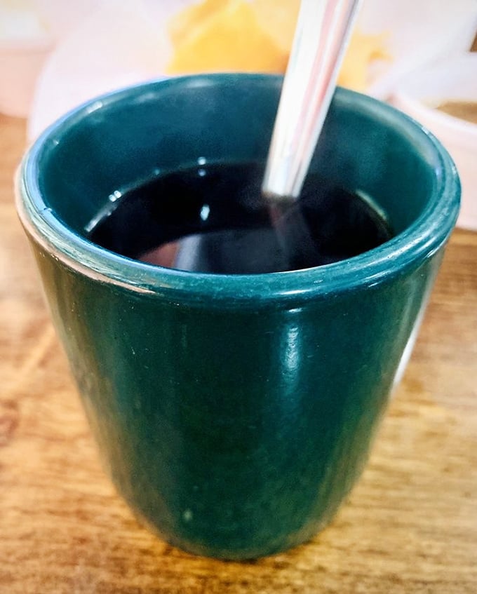 That simple green mug holds liquid motivation—strong, no-nonsense coffee that doesn't need fancy latte art to get the job done right.
