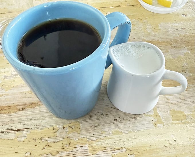 Coffee served in a cheerful blue mug with a side of cream—the morning ritual that makes everything else possible.