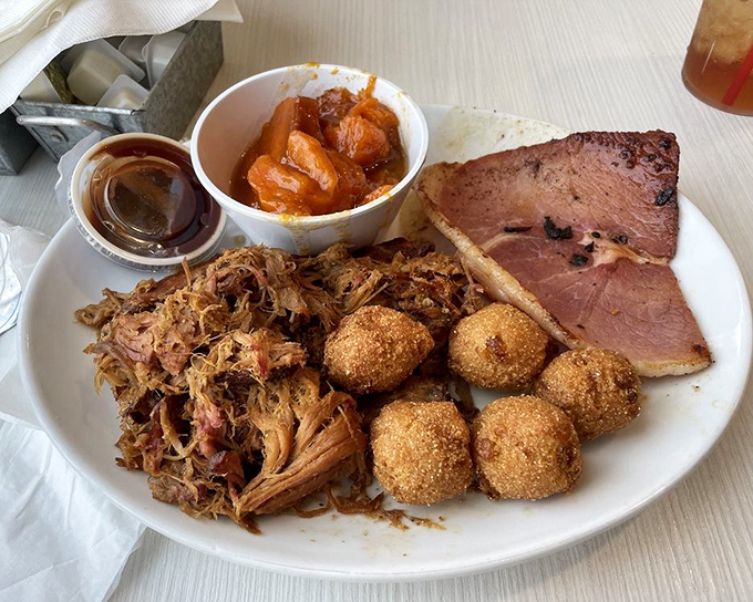 BBQ heaven on a plate – pulled pork, country ham, and hush puppies create a trifecta of Southern flavors that demands to be savored.