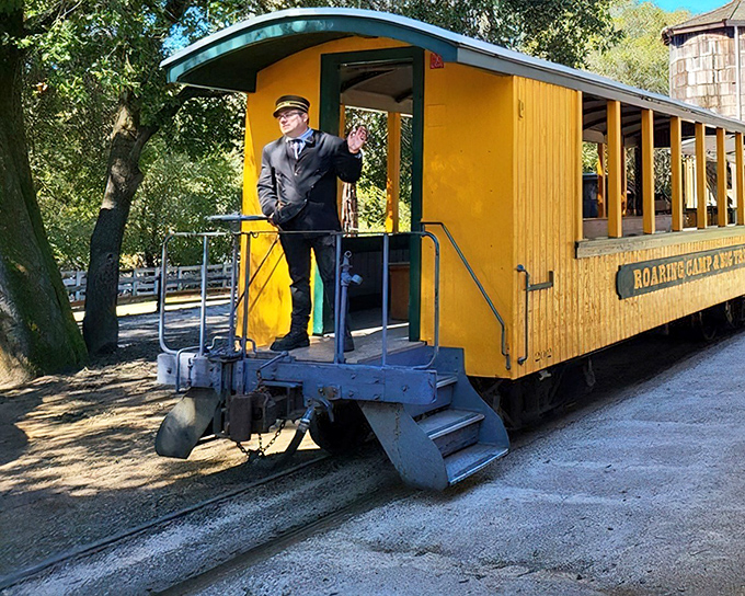 The conductor, complete with classic uniform and cap, stands ready to guide visitors on their journey—the human connection to railroading history.