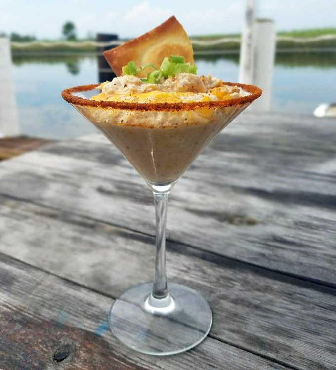 This martini glass isn't holding a cocktail—it's showcasing crab dip with the waterfront view providing the perfect garnish.