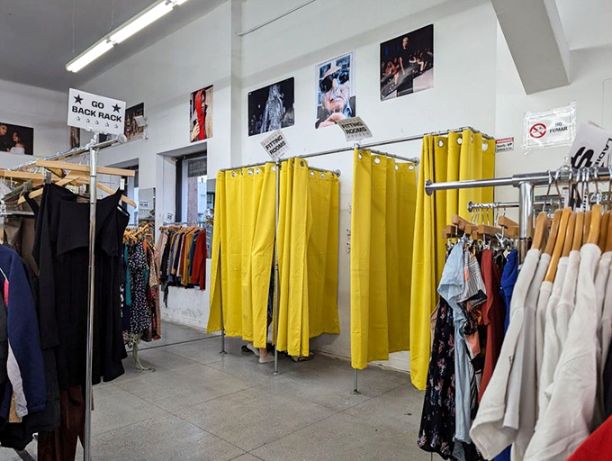 The yellow curtain sanctuaries – where hopeful shoppers perform the universal "does this actually fit me?" dance.