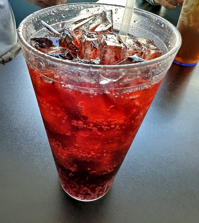 That cherry-red soda isn't just a drink—it's summer in a glass, childhood memories with ice, and the perfect companion to anything fried.