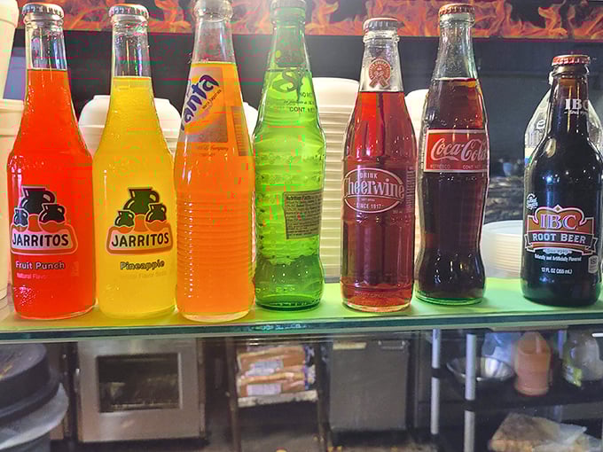 A rainbow of bottled sodas stands at attention, offering sweet relief from the savory smoke parade happening on your plate.