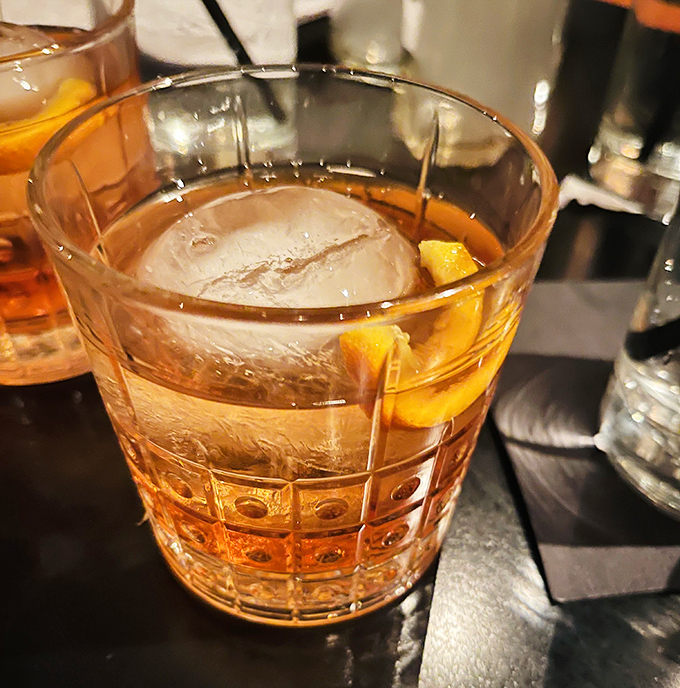 An Old Fashioned that Don Draper would approve of—amber liquid, oversized ice cube, and just enough orange zest to make things interesting.