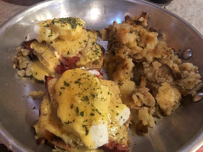 Eggs Benedict that's dressed for success—the hollandaise draped over everything like a yellow velvet robe, with home fries playing the perfect supporting role.