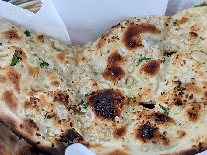 Garlic naan with those perfect char spots is the unsung hero of Indian cuisine – part utensil, part side dish, all delicious.