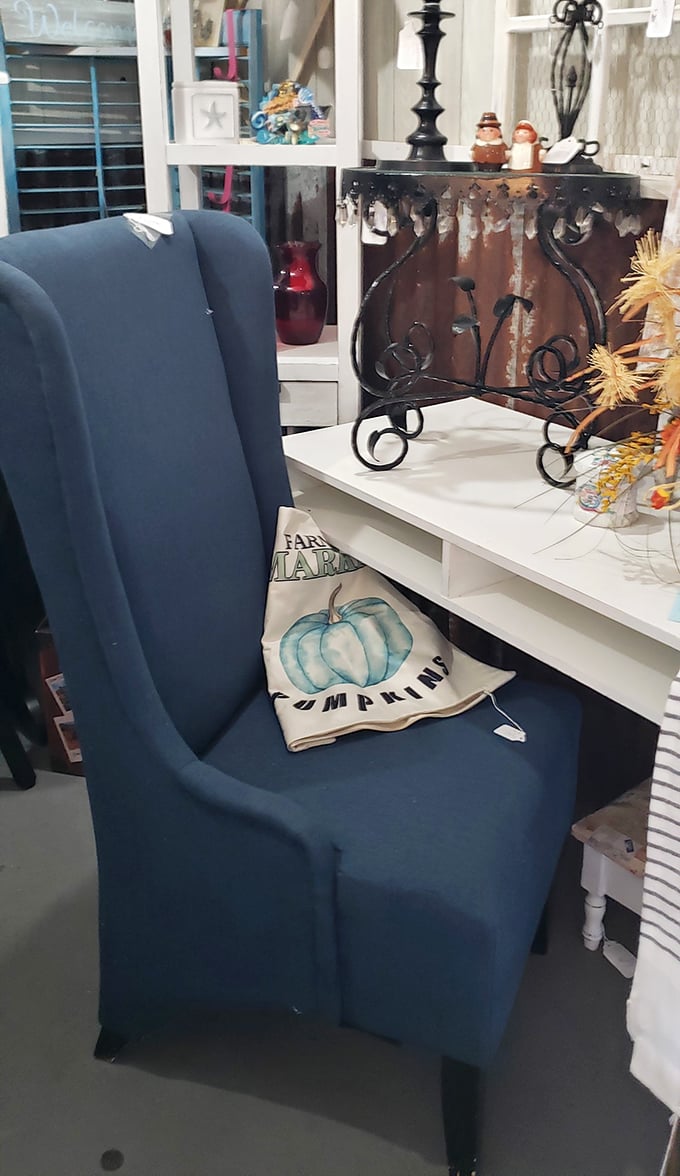 A navy wingback chair paired with a farmhouse pumpkin pillow—the furniture equivalent of comfort food with a seasonal twist.
