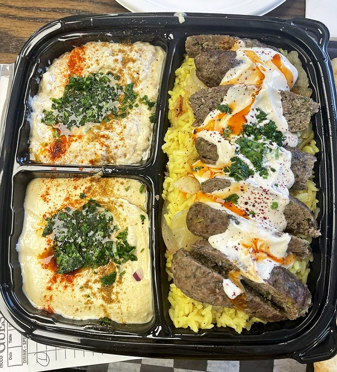 Kafta kabobs lounging on a bed of yellow rice with hummus on the side—a Middle Eastern feast that feels like a warm hug.