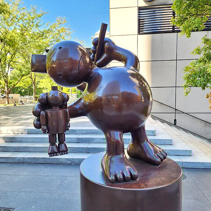 This whimsical bronze figure holding what appears to be a smaller companion creates a delightful parent-child dynamic. Playfulness in sculptural form.