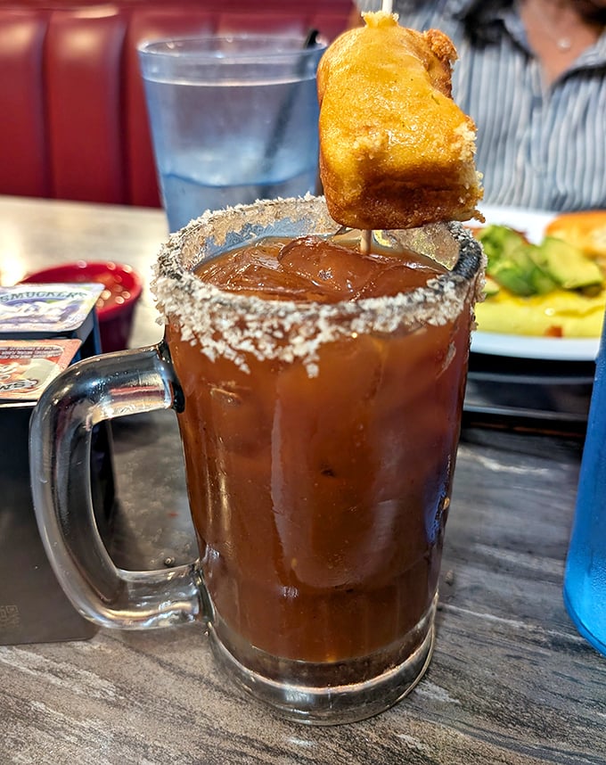 The Bloody Mary's brawnier cousin—a Michelada with enough garnish to qualify as an appetizer. That fried nugget perched on top isn't just decoration.