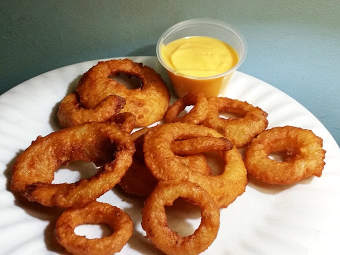 Golden onion rings that shatter with each bite, paired with a dipping sauce that makes you wonder why you don't eat these every day.