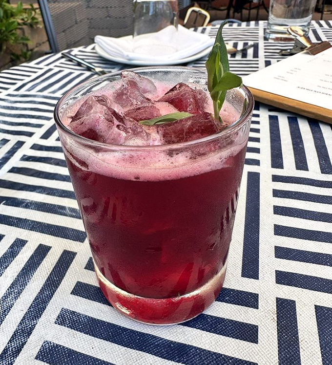 This ruby-red cocktail, garnished with fresh herbs, isn't just a drink—it's liquid courage before your meat adventure begins.