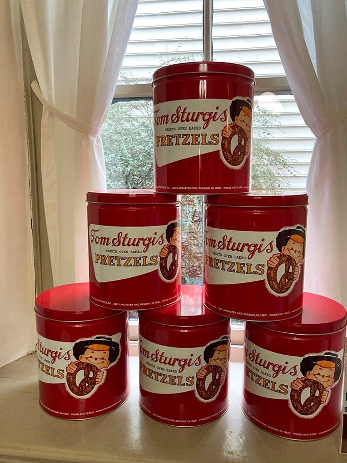 Vintage red pretzel tins stacked by the window—collectibles that actually contain something worth collecting besides dust and regret.