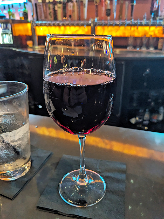 A glass of robust red wine waiting patiently at the bar – because every great meal deserves an equally distinguished liquid companion.