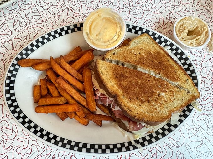 The perfect Reuben isn't just a sandwich—it's architecture. Those sweet potato fries on the side? The supporting cast that steals the show.
