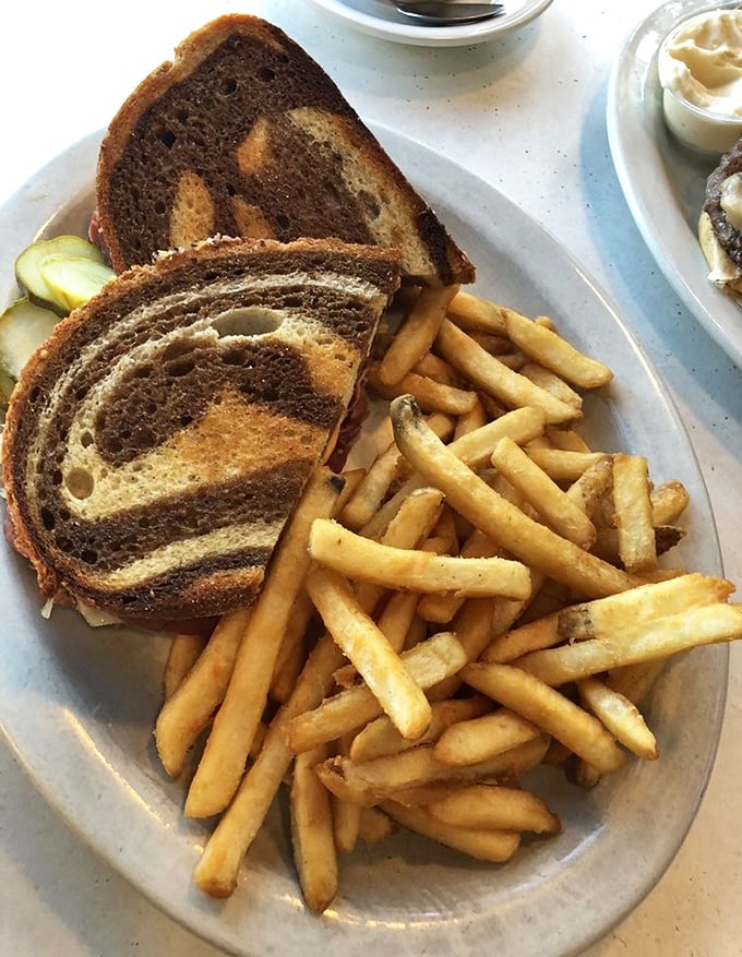 The Reuben sandwich—where marble rye, corned beef, and sauerkraut perform a perfectly choreographed dance of flavor, with fries as the adoring audience.