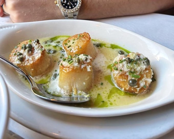 Golden seared scallops swimming in butter sauce with capers—ocean candy that makes you wonder why we bother with actual dessert.