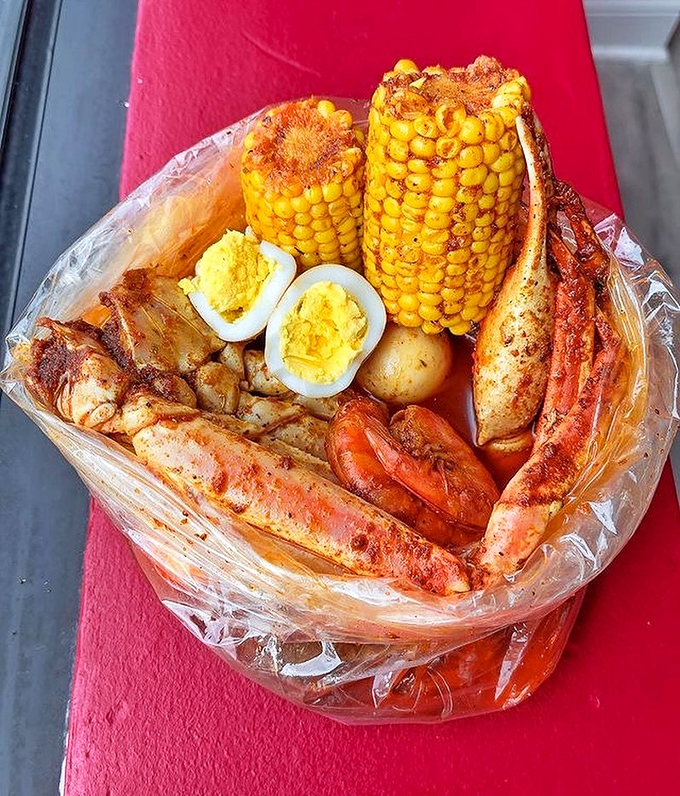 The seafood boil arrives like a treasure chest—crab legs, corn, potatoes, and eggs swimming in seasoned glory, all sealed in plastic for maximum flavor infusion.
