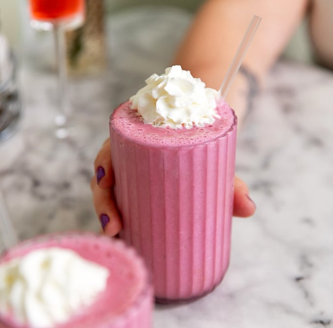 This pink smoothie isn't just a drink—it's a portable happiness machine topped with a cloud of whipped cream.