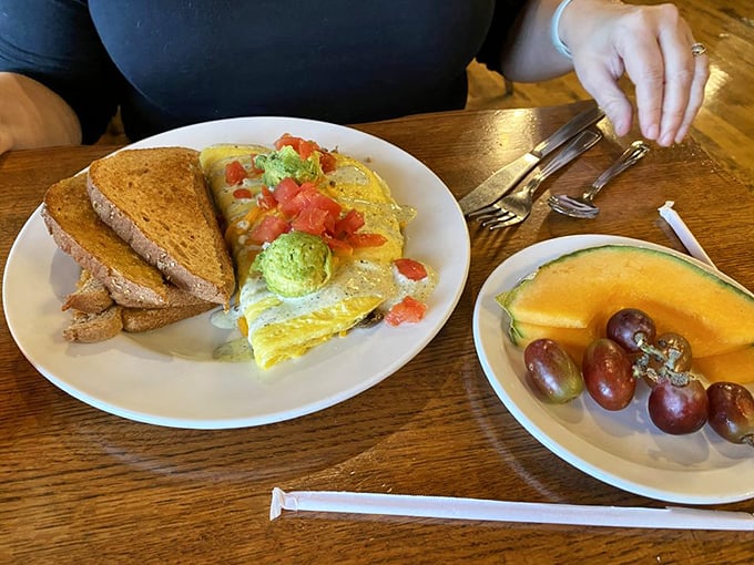 Breakfast architecture at its finest – an omelet stuffed with avocado and topped with fresh tomatoes, with fruit providing a sweet counterpoint.