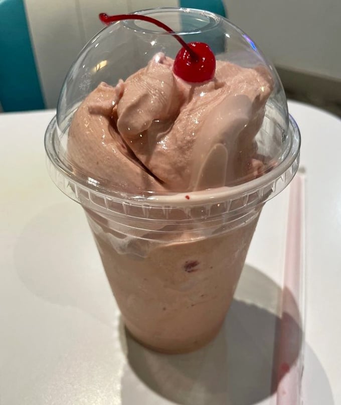 The strawberry shake topped with a ceremonial cherry—dessert masquerading as a beverage, and nobody's complaining about the deception.