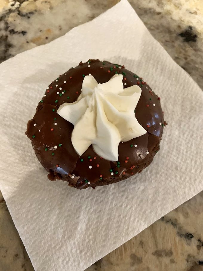 A chocolate donut wearing its holiday best – festive sprinkles and a cream star that's dressed for the occasion.