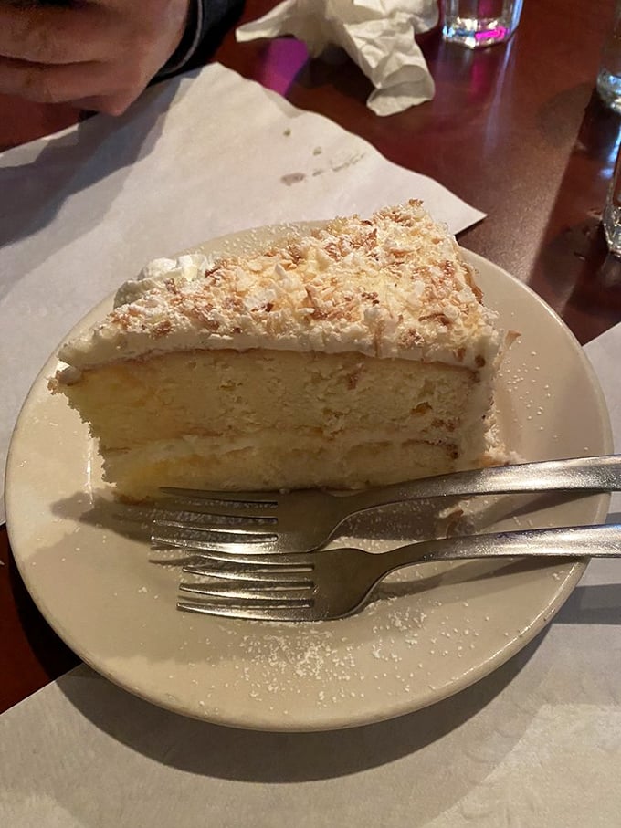 A slice of coconut cake so ethereal it deserves its own Instagram account – the kind of dessert that makes you consider ordering a second piece before finishing the first.