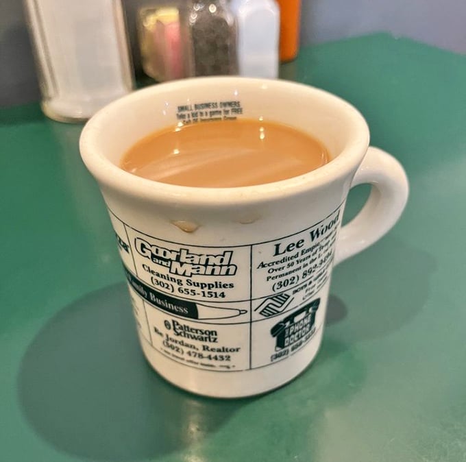 Coffee served in a mug advertising local businesses – because in a proper diner, even your caffeine supports the community.