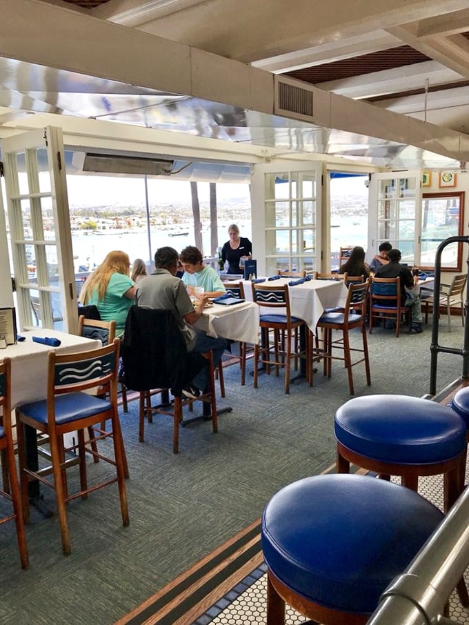 The dining room buzzes with conversation as patrons enjoy the ultimate dinner theater – Newport Harbor's constant parade of boats and seabirds.