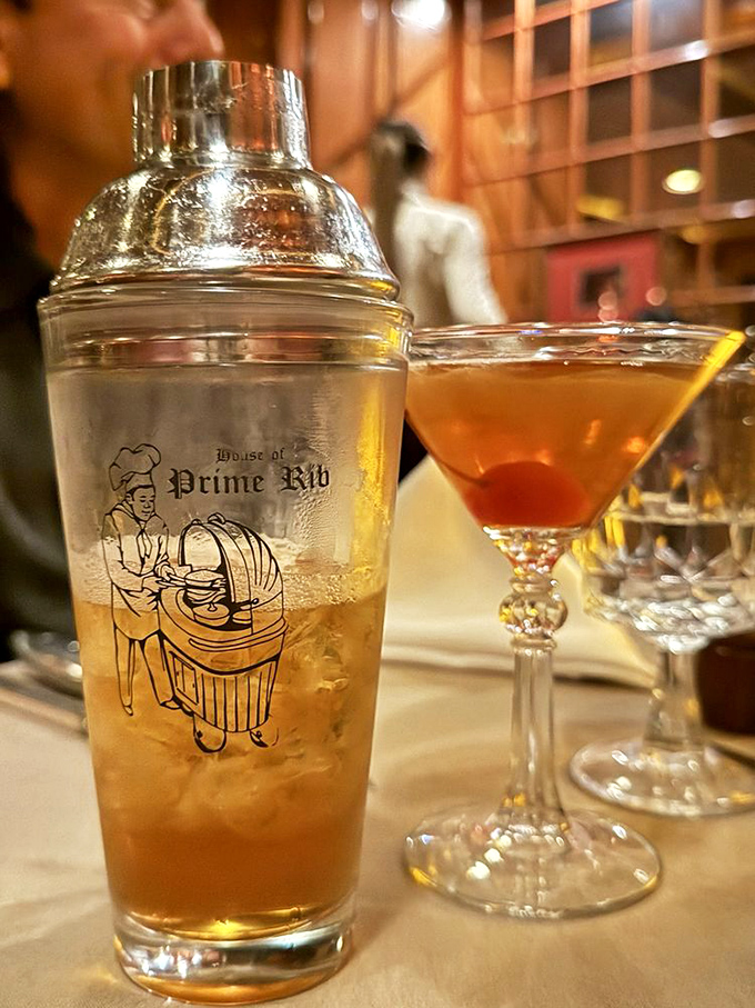 Classic cocktails served in proper glassware—because your Manhattan deserves better than a plastic cup. The martini shaker hints at proper priorities.