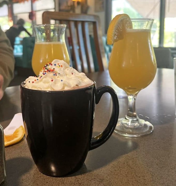 Hot chocolate topped with whipped cream and sprinkles alongside mimosas—because sometimes breakfast calls for both childhood joy and adult privileges.