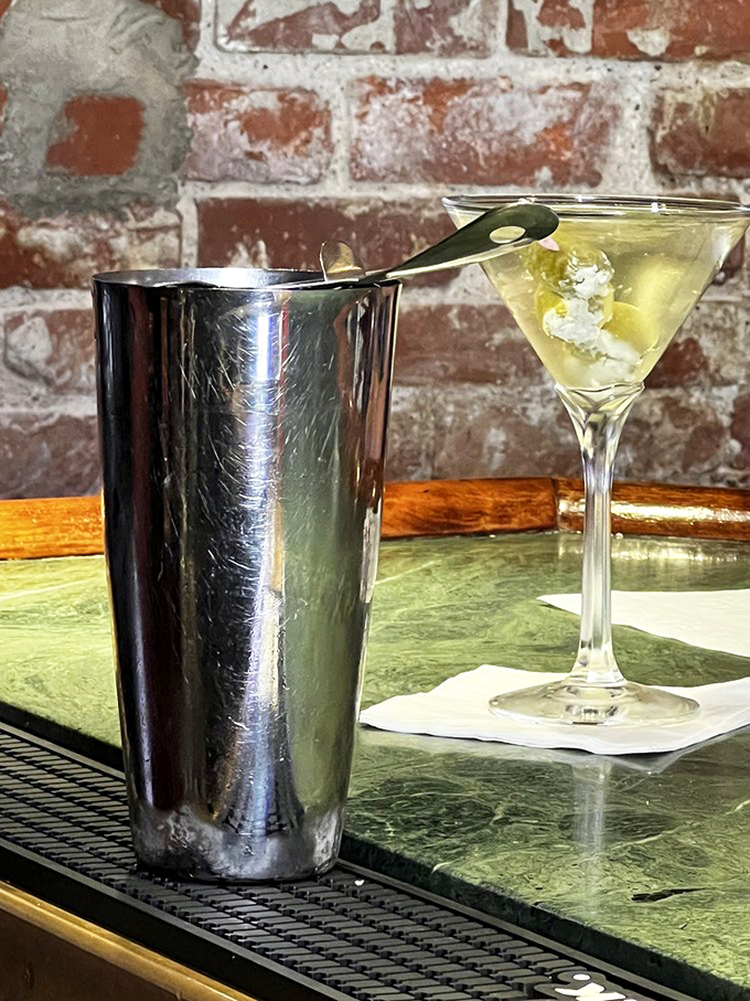 The martini sits elegantly against exposed brick—a timeless pairing that says "your day is officially over, and the good part has begun."