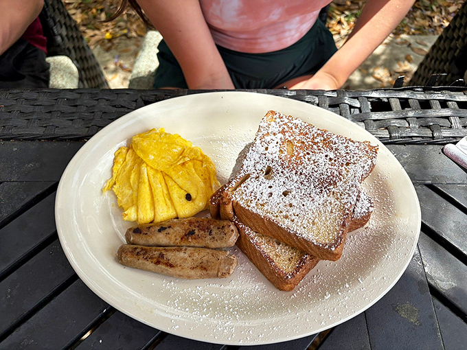 French toast dusted with powdered sugar, alongside sausage links and eggs—breakfast's holy trinity performing in perfect harmony.