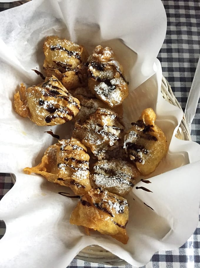 Fried bananas dusted with powdered sugar and chocolate drizzle—proof that dessert doesn't need to be complicated to be transcendent.